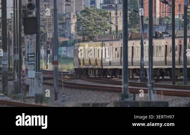 A yellow train moves along the tracks through a busy urban area in the ...