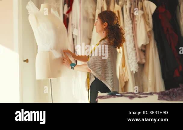 Female fashion designer creating a bespoke white wedding gown on a ...