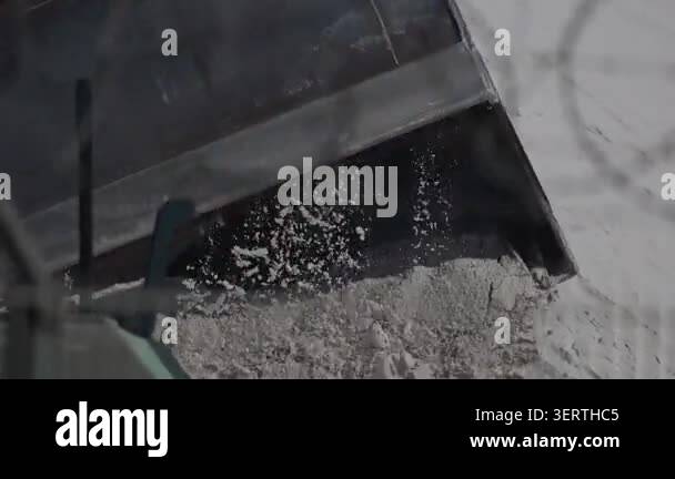 Workers operate large machinery to move and load sand at a construction ...