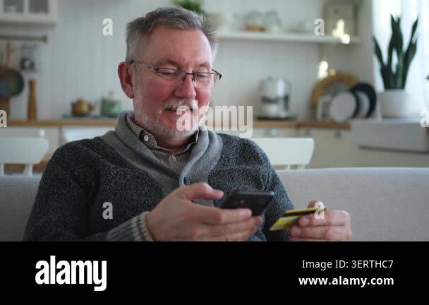 Senior man shopping online holding smartphone paying with credit card ...