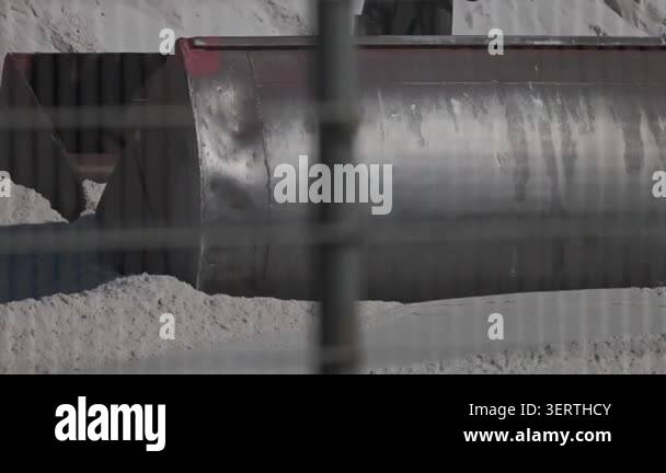 Workers operate large machinery to move and load sand at a construction ...