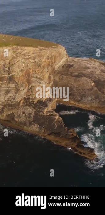 Dramatic ocean waves crash against ancient sea cliffs at a rugged ...