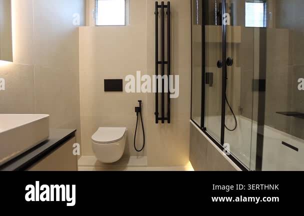 Clean residential bathroom with beige walls, a wall-mounted toilet ...