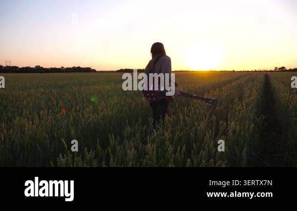 Young male hipster with long hair holding electric guitar in hand and ...