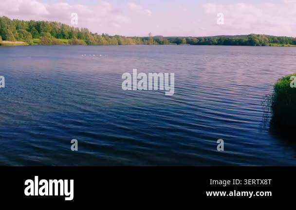View of lake blue water by shore side wide aerial drone zoom shot ...