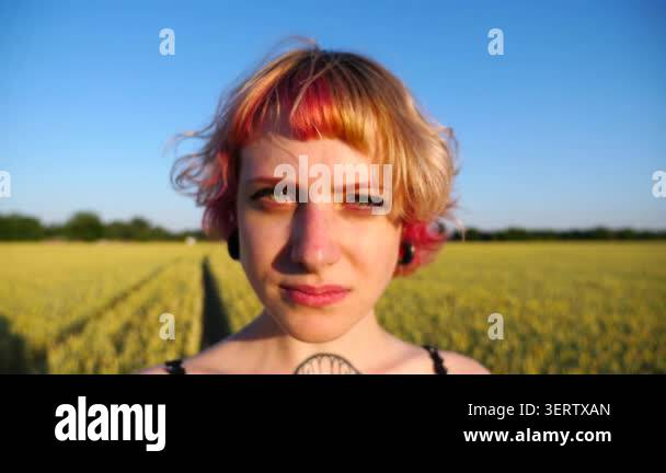 Cheerful punk girl with ear tunnels making funny face while wiping ...