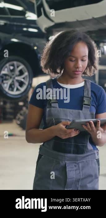 Portrait of Smiling African American woman, a car mechanic using a ...