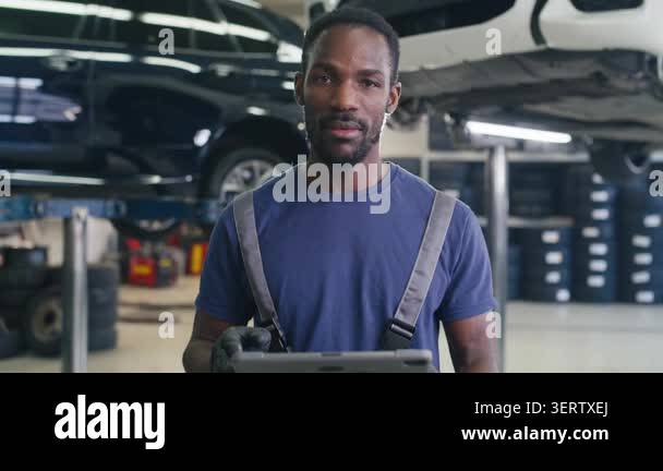 Portrait of a smiling car mechanic or automotive technician, in a work ...