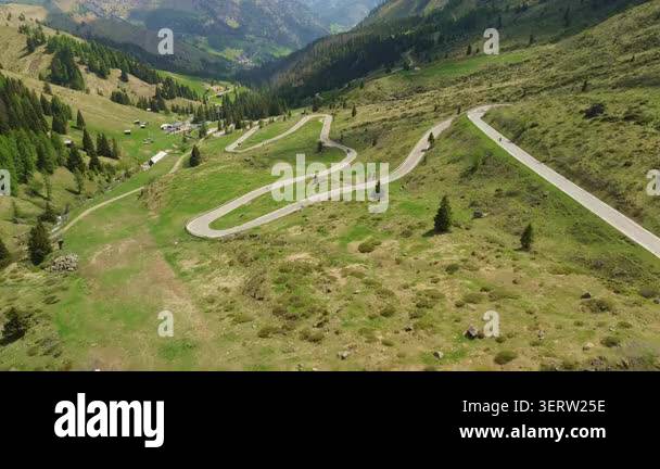 Aerial view of a curving paved road cutting through a green mountain ...
