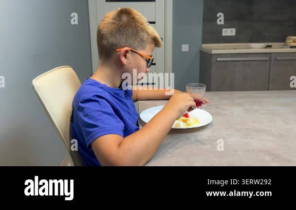A young boy sits at the left foreground of a modern kitchen island ...