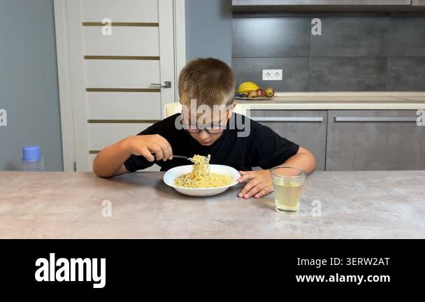 A young blond boy wearing glasses sits at a modern kitchen island ...