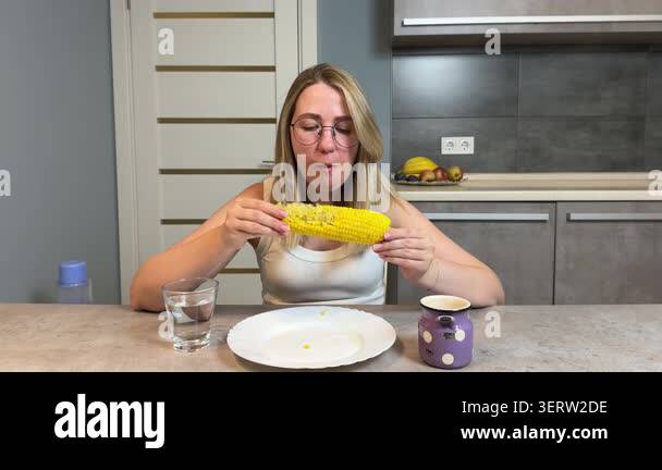 Young woman wearing glasses and a white sleeveless top sits at a ...