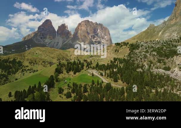 Wide aerial view of a green alpine valley with a curving road ...