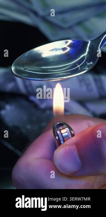 Man is cooking heroin in spoon with white drug powder, money and ...