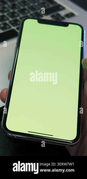 Smartphone with green screen in male hand. Man is sitting in office and ...