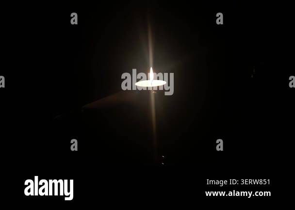 A lit candle glowing intensely with a strong vertical light flare in a ...