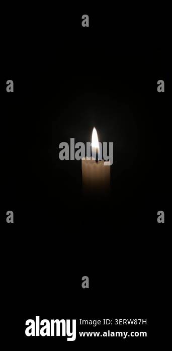 A single lit candle with melted wax and a bright flame against a black ...