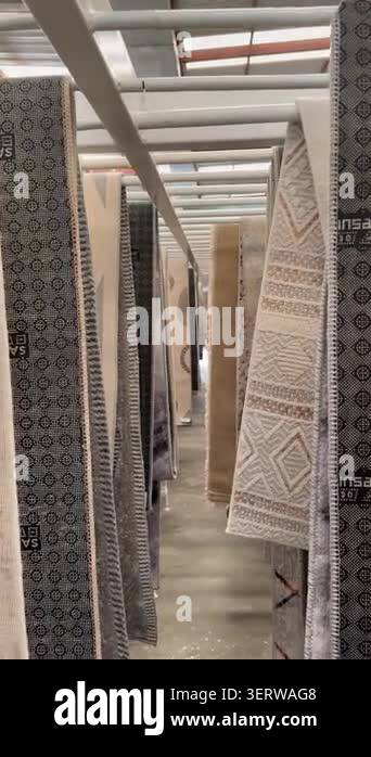 Rows of decorative textile samples hang from overhead racks in a narrow ...