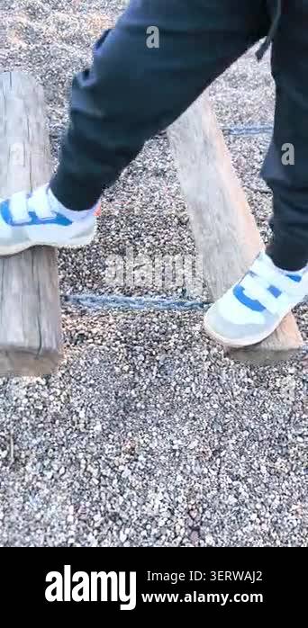 A close-up of a childs feet in sneakers carefully stepping across the ...