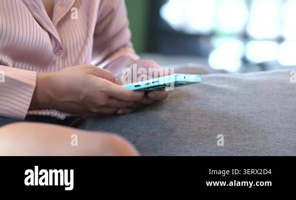 Woman using smartphone while sitting on sofa at home. online ...