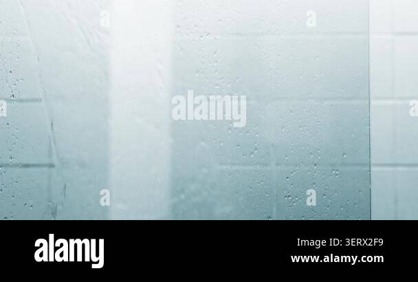 Water flowing behind a shower glass with droplets on the surface. Water ...