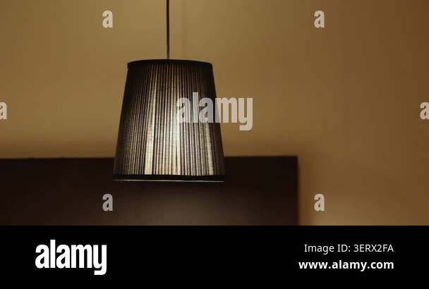 Bedside lamp switching on and off in a bedroom. Hanging pendant lamp ...