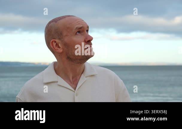 A frontal portrait of a calm Caucasian man with a subtle, neutral ...