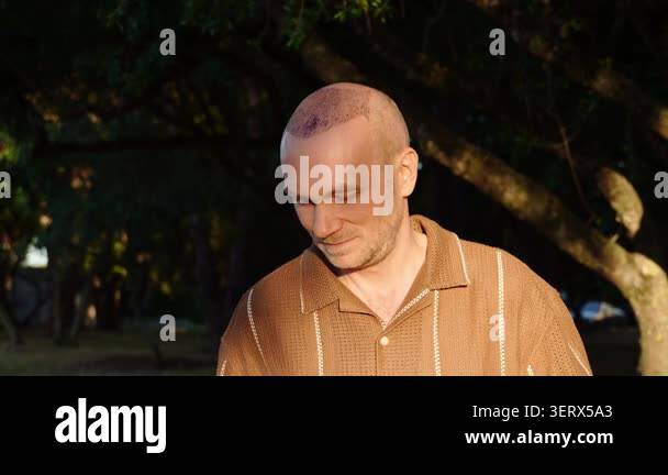 A portrait of a calm and content Caucasian man in a brown polo shirt ...