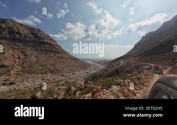 Rocky mountain valley with a winding dirt road and narrow river leading ...