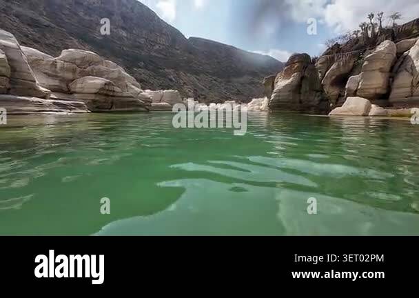 Calm green water flowing between rocky canyon walls under a cloudy sky ...