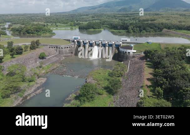 Aerial View of a Modern Dam Surrounded by Lush Greenery and a Calm ...