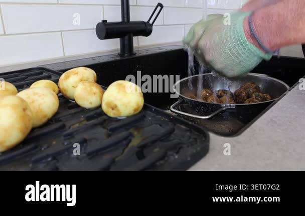 Stockholm, Sweden A man in a residential kitchen uses coarse gloves ...