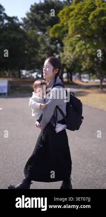 Woman carrying baby while walking outdoors Stock Video Footage - Alamy