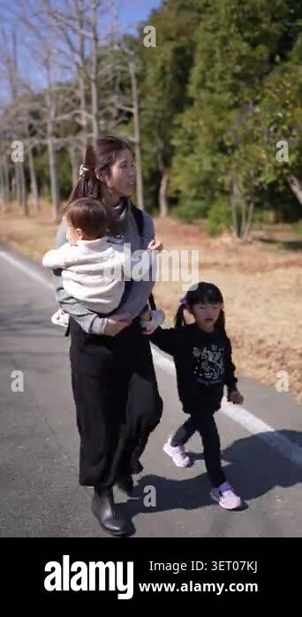 Woman carrying baby walking beside child Stock Video Footage - Alamy