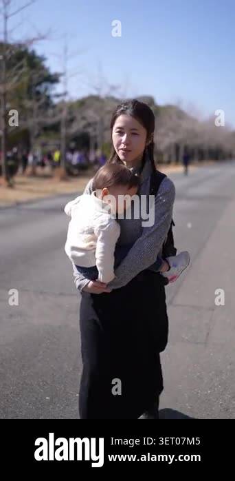 Woman holding baby standing on empty street Stock Video Footage - Alamy