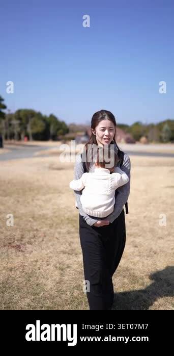 Woman carrying baby walking on grassy field Stock Video Footage - Alamy