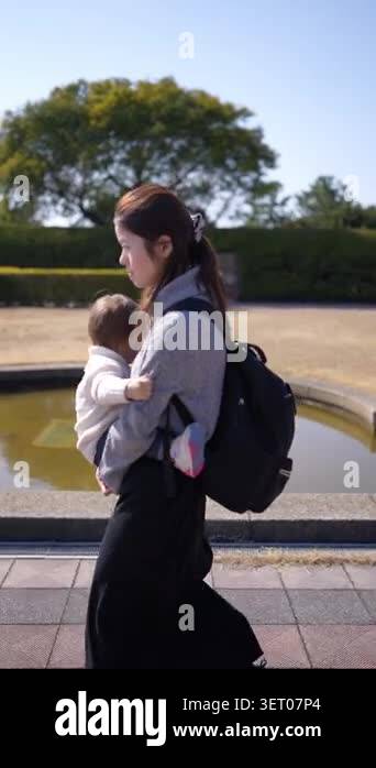 Woman carrying baby walking near pond Stock Video Footage - Alamy