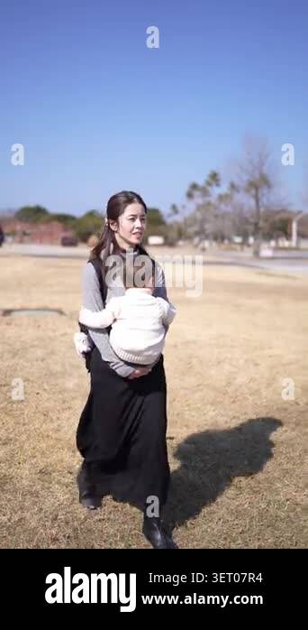 Woman carrying baby walking on grassy field Stock Video Footage - Alamy