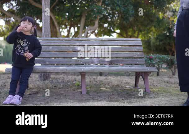 Girl sitting on wooden bench under green trees Stock Video Footage - Alamy