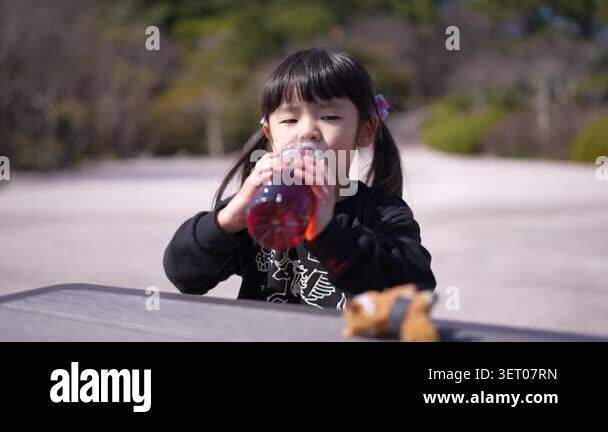 Young girl drinking beverage while sitting outdoors Stock Video Footage ...