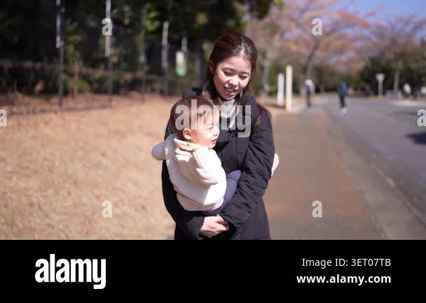 Woman holding child walking in park Stock Video Footage - Alamy