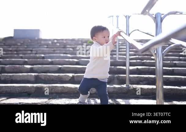 Toddler climbing stairs holding onto railing Stock Video Footage - Alamy