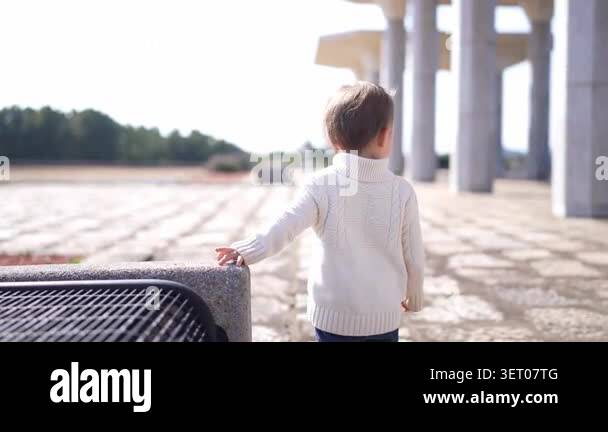 Child walking away wearing white sweater Stock Video Footage - Alamy