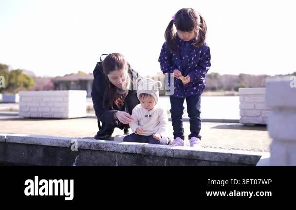 Woman helping child while another girl watches Stock Video Footage - Alamy