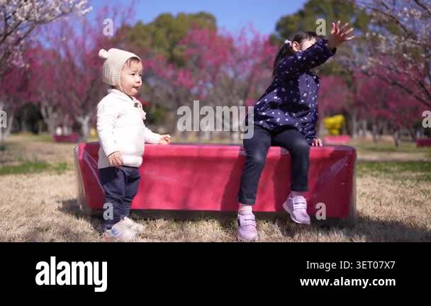 Two children playing outside near pink flowers Stock Video Footage - Alamy