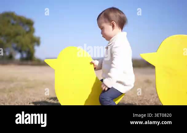 Child playing outdoors on yellow bird sculpture Stock Video Footage - Alamy