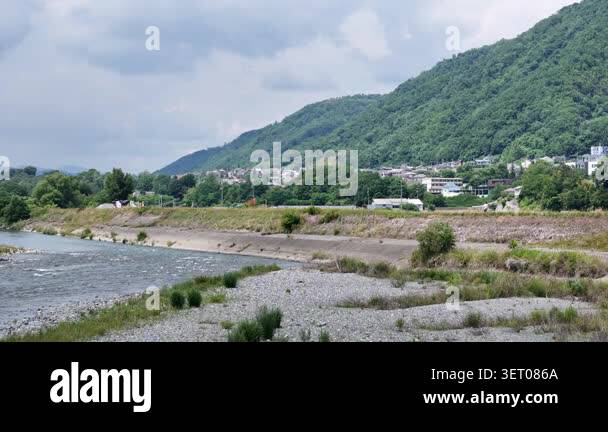 Riverbank view with mountains and cloudy sky Stock Video Footage - Alamy