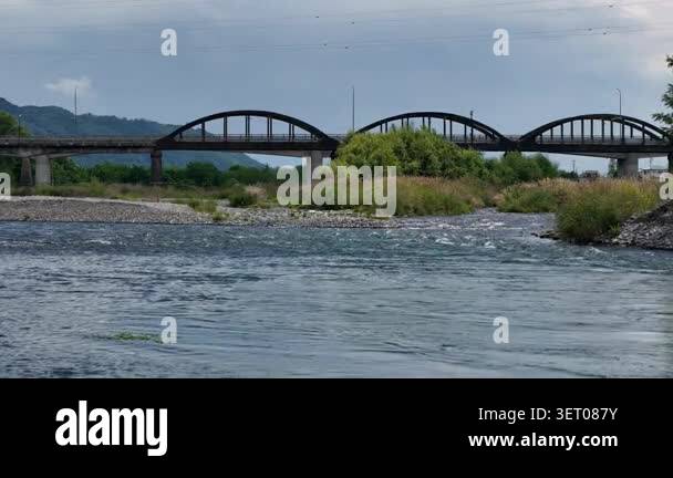 Bridge spanning over calm river with greenery Stock Video Footage - Alamy