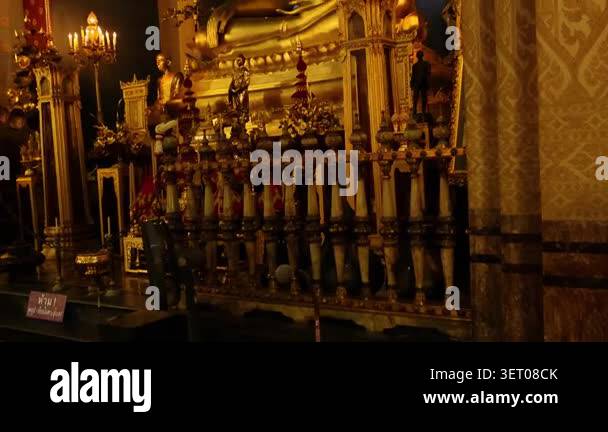 Golden buddha altar with flickering candlelight and rows of offering ...