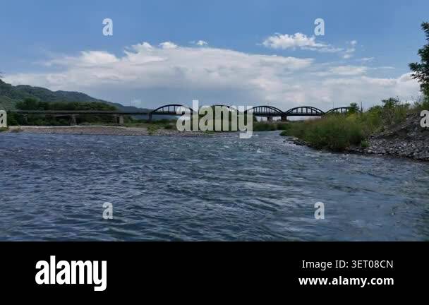 River flowing under bridge with green vegetation Stock Video Footage ...